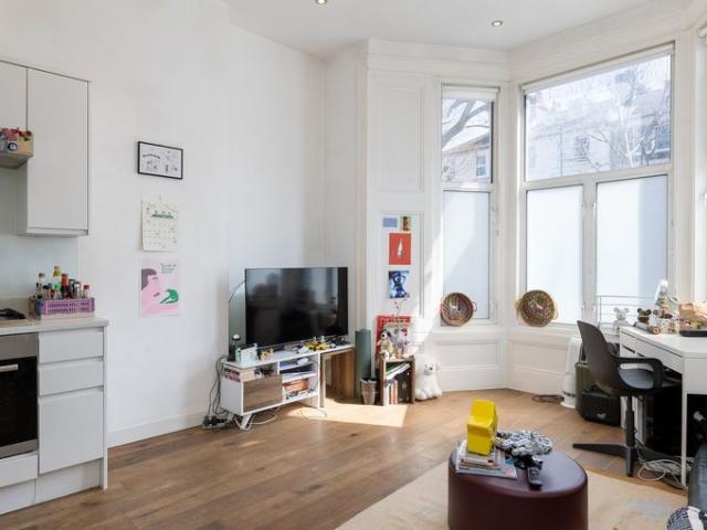 A smart refurbished apartment benefitting from large windows, wooden floors, open plan kitchen, bedroom with built in storage and a stylish bathroom